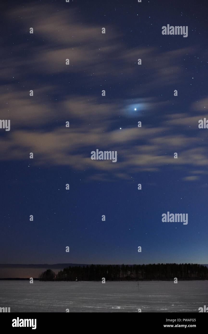 Conjuction of planets Jupiter and Venus on night sky above snowy winter ...