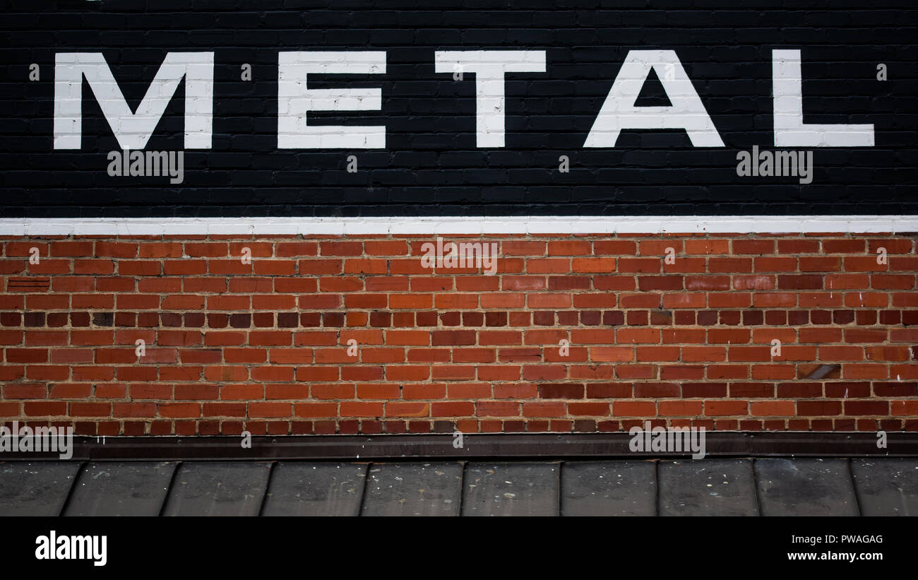 Metal sign on antique brick wall above awning along rural city street ...