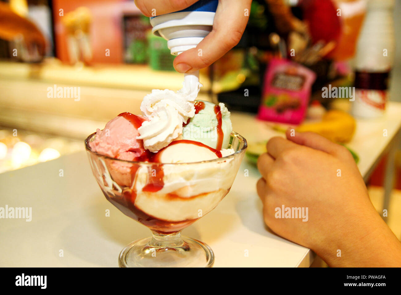 Female Seller pours sauce on ice cream. Woman hard making ice cream ...