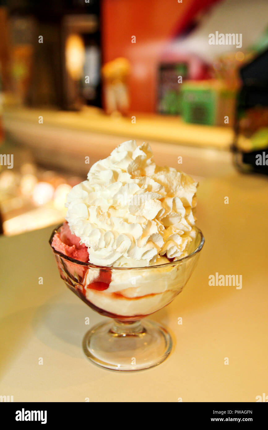 Female Seller pours sauce on ice cream. Woman hard making ice cream ...