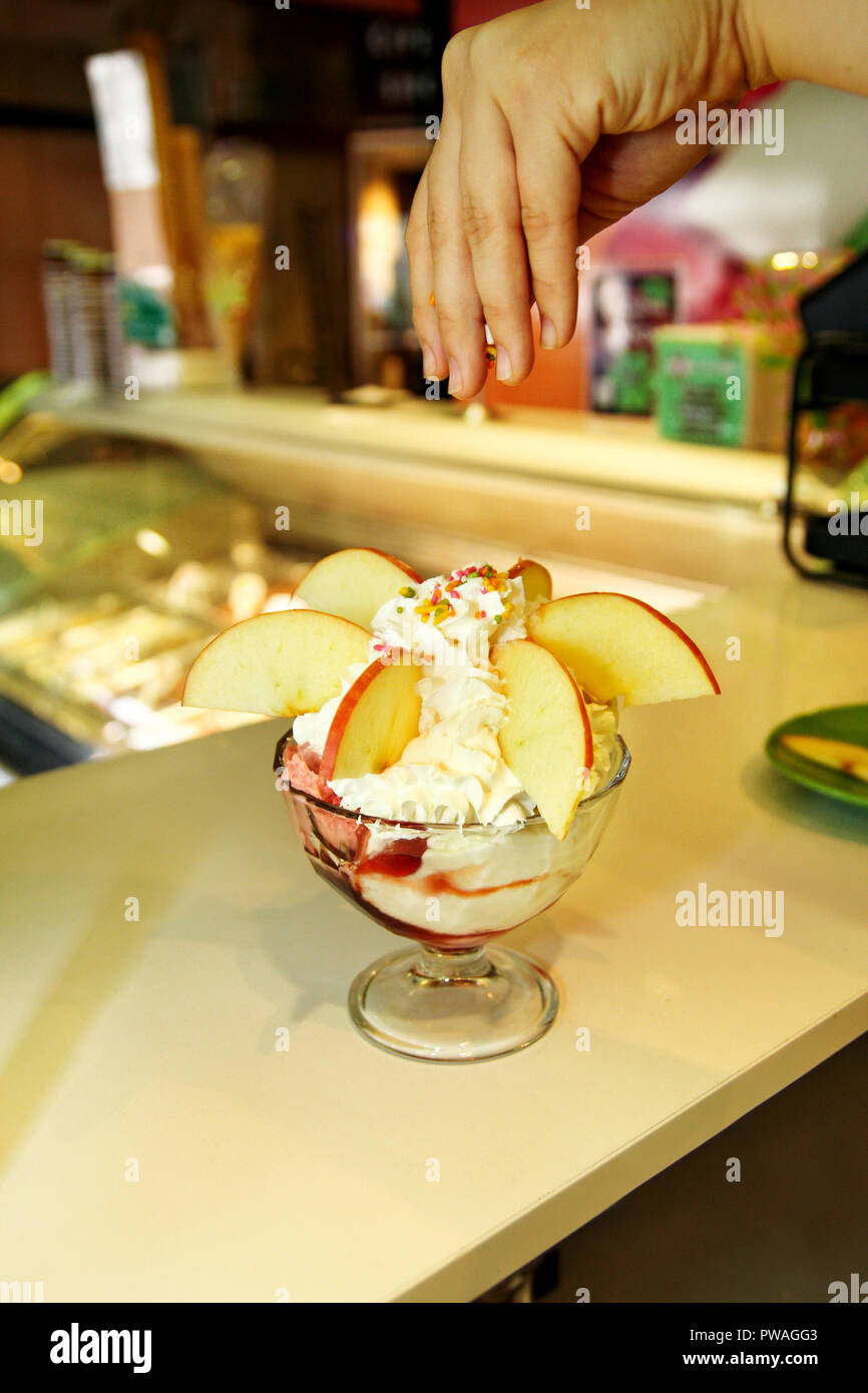 Female Seller pours sauce on ice cream. Woman hard making ice cream ...
