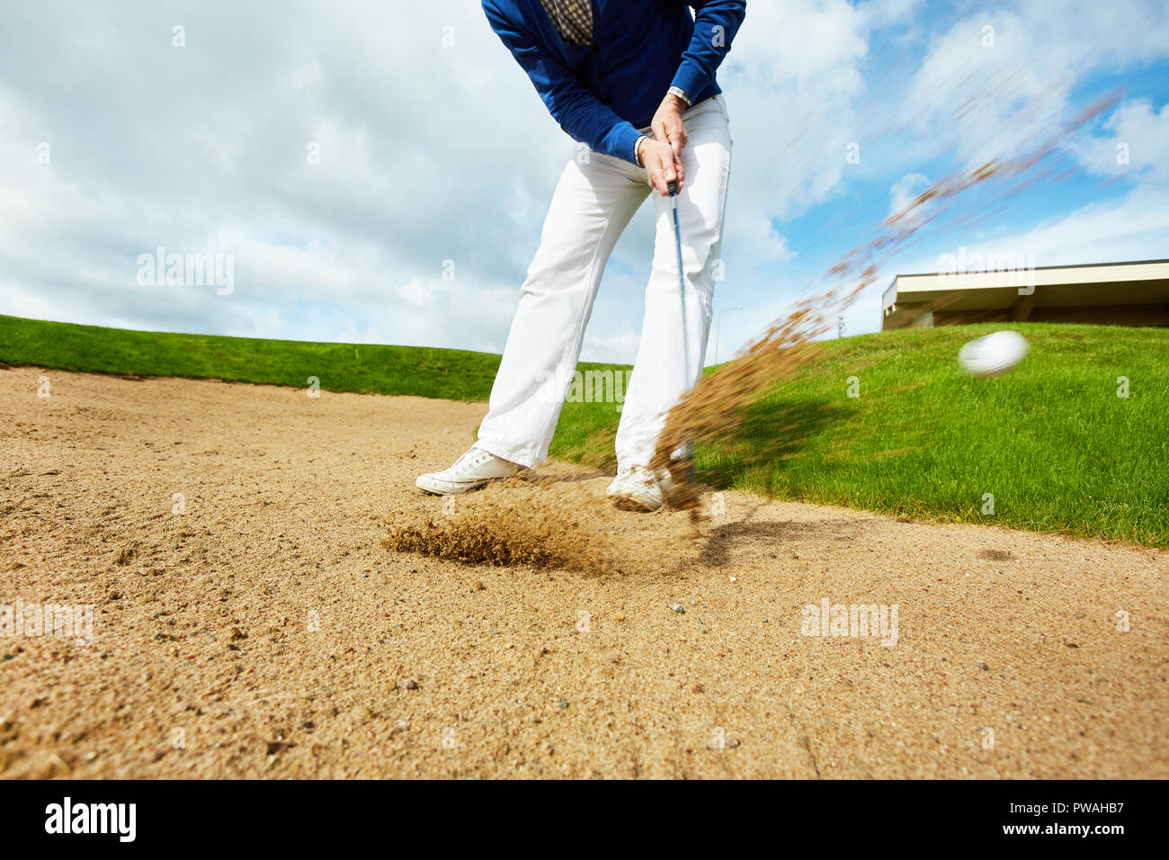 Active man hit golf ball by club while standing on the ground and ...