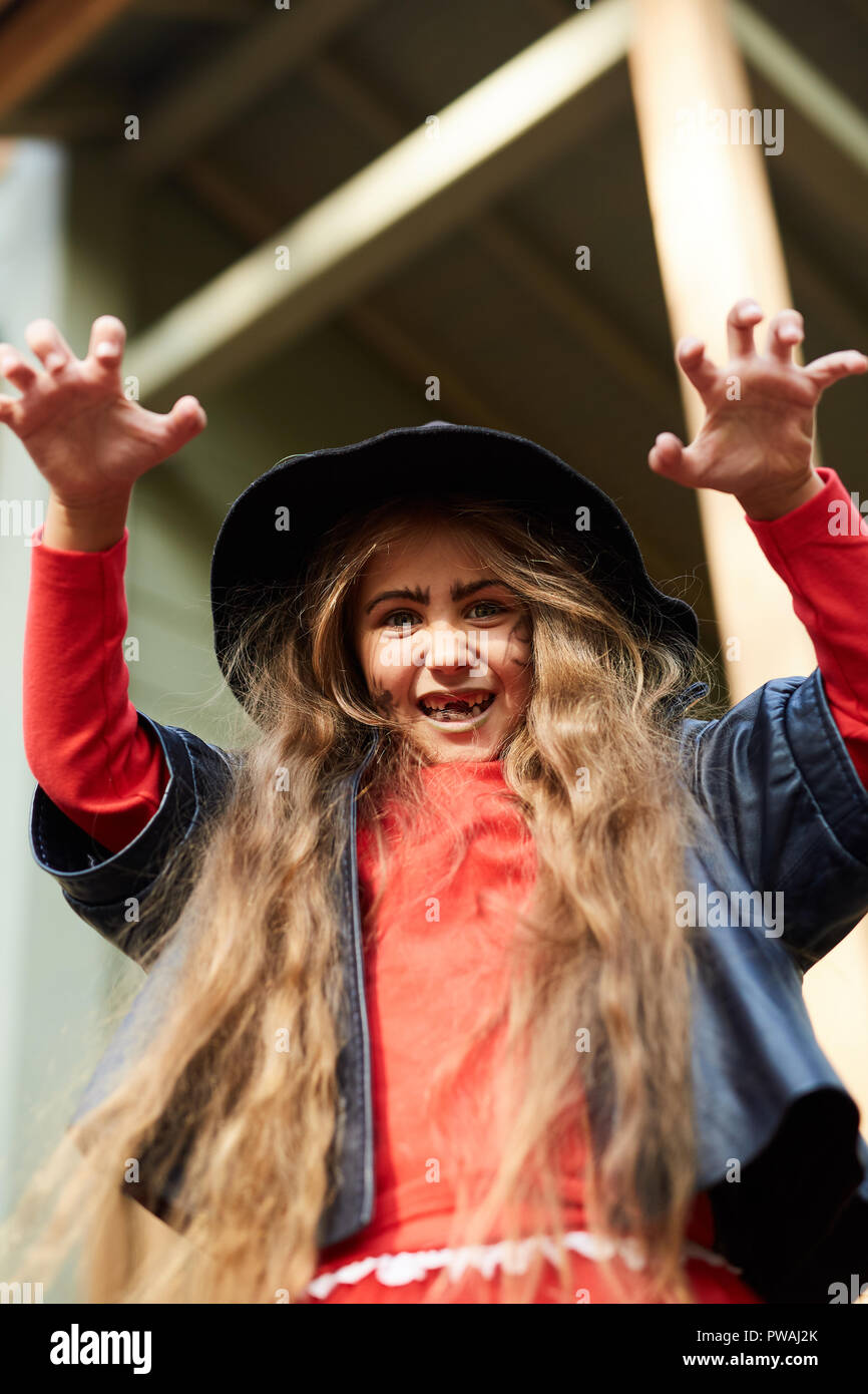 Little girl with long brown hair making cat claws gesture while looking ...