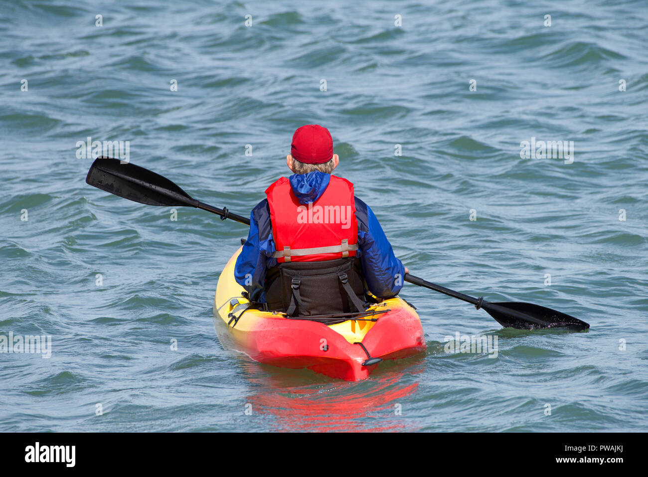 Elderly kayaker enjoying healthy sport exercise in calm bay waters ...