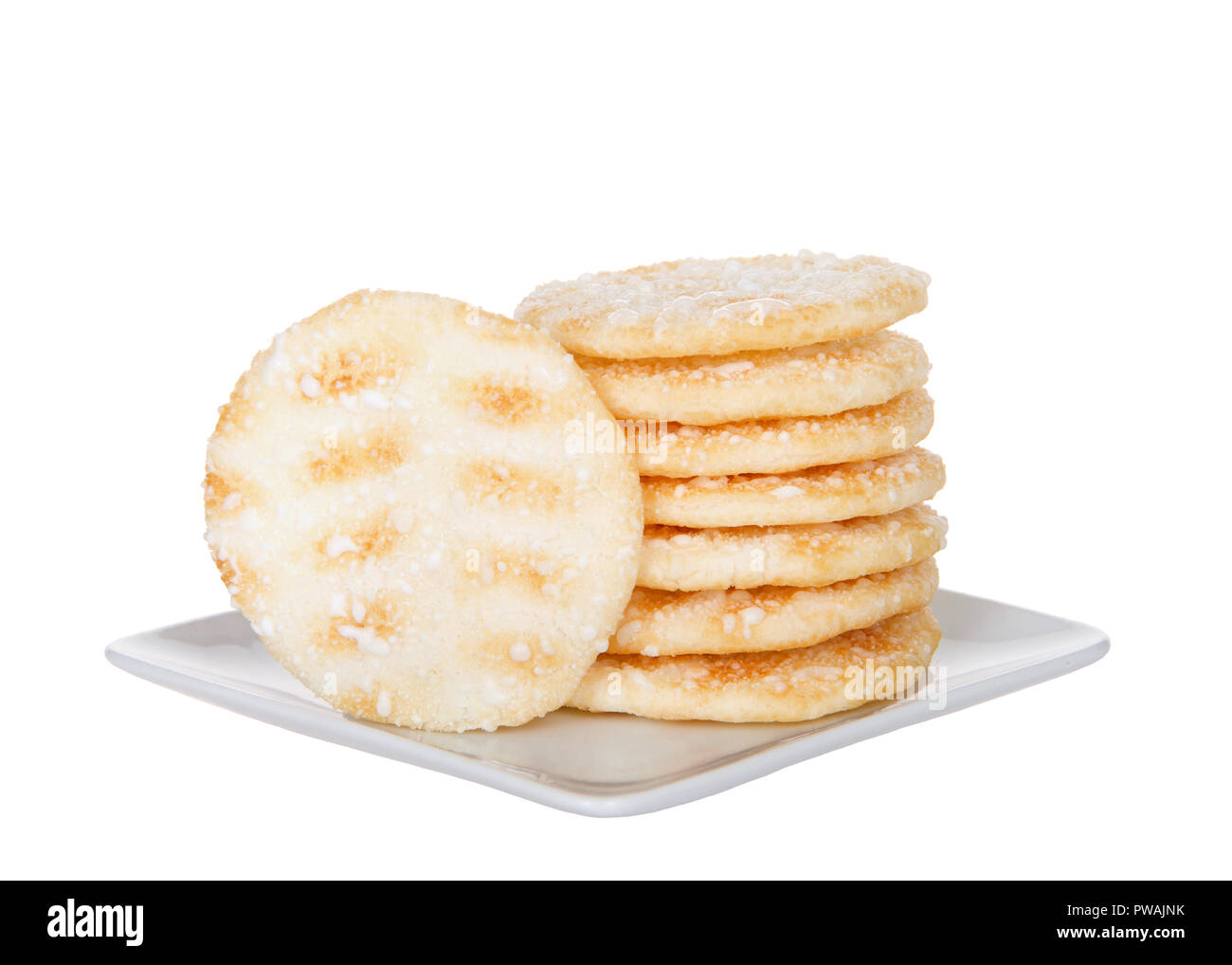 Pile of Japanese rice crackers on a small white square porcelain plate ...