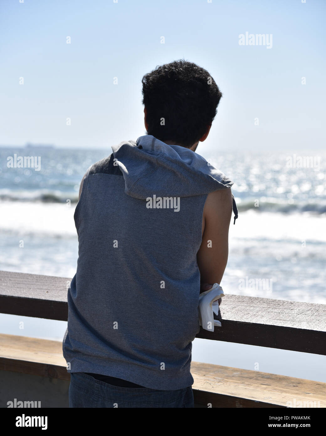 A young man on a pier looking out over the ocean Stock Photo - Alamy