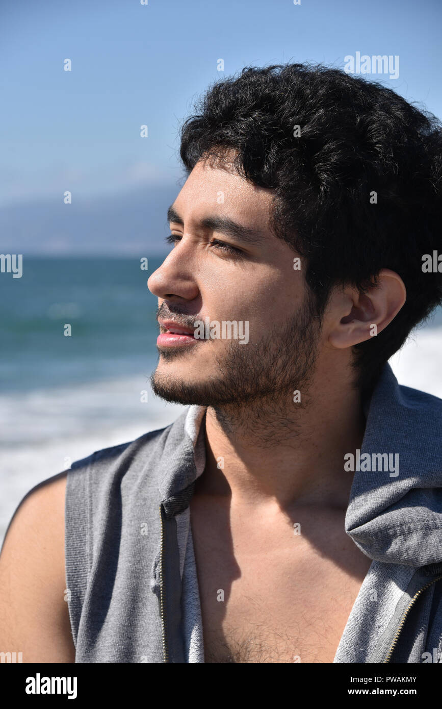 A handsome dark complected young man enjoying the view at the ocean ...