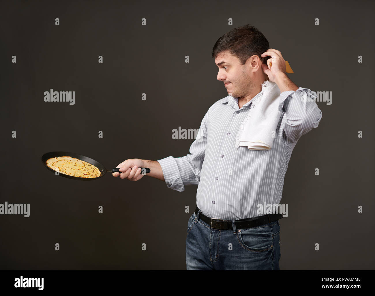 man posing with a pancake in a pan, white shirt and pants, gray ...