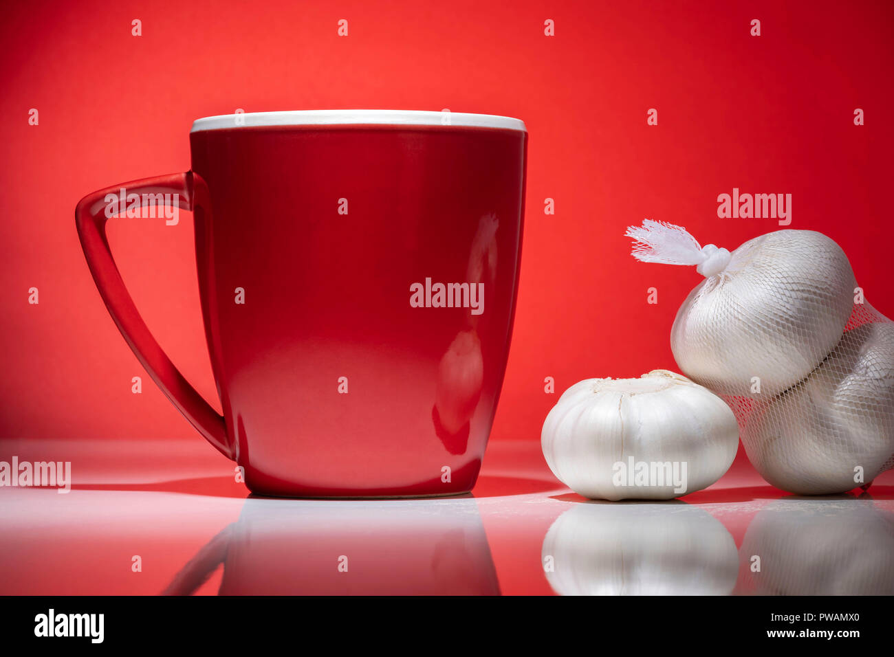 Red mug with small pile of garlic isolated on the red background Stock ...