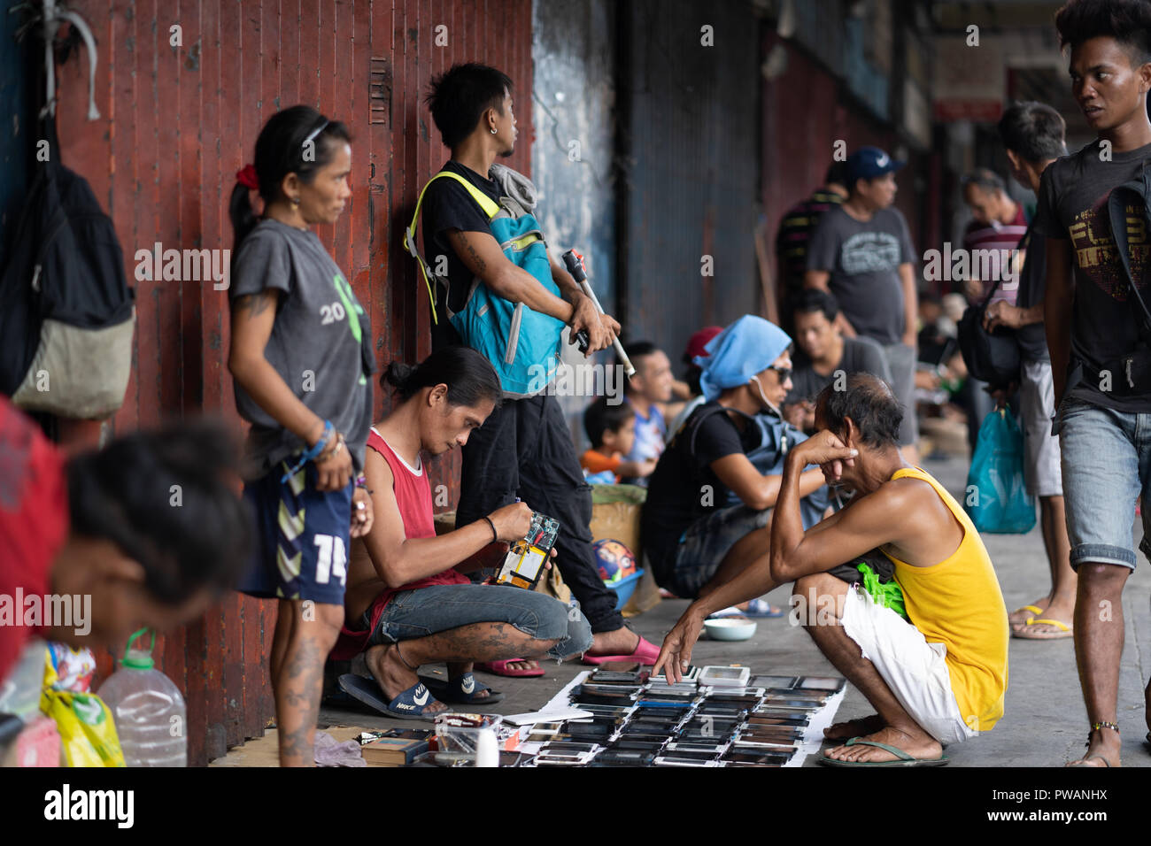Filipino trader repairing and selling secondhand mobile phones on a ...