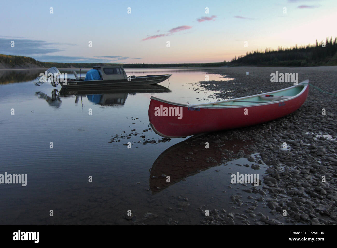 Yukon river, Yukon Territory, Alaska. Canoe and outboard resting on the ...