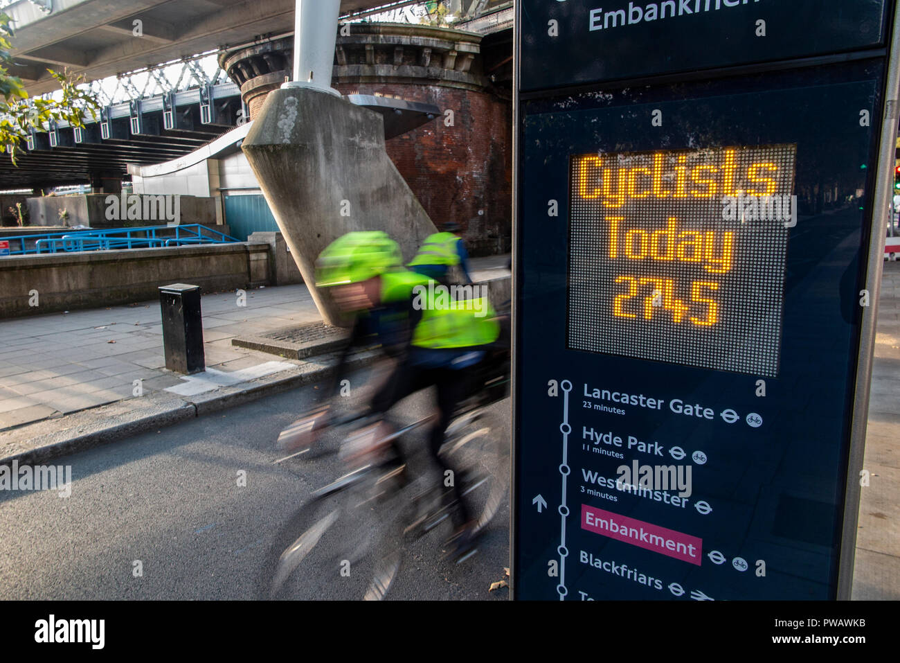 Riders cycling through a digital bicycle rider counter in London Stock ...