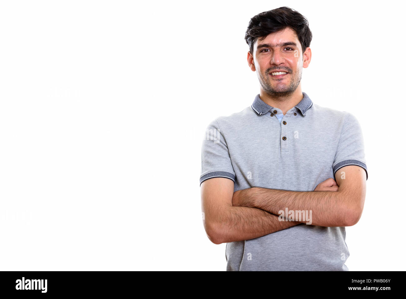 Studio shot of young happy Persian man smiling with arms crossed Stock ...