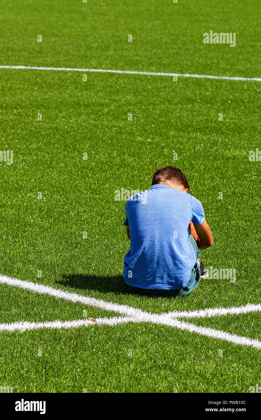 Sad disappointed boy sitting on the grass in stadium Stock Photo - Alamy