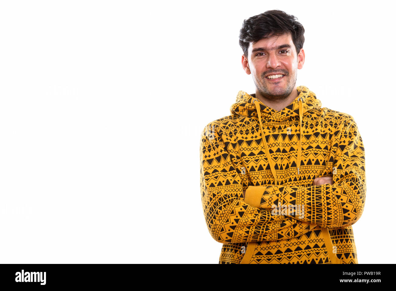 Studio shot of young happy Persian man smiling with arms crossed Stock ...