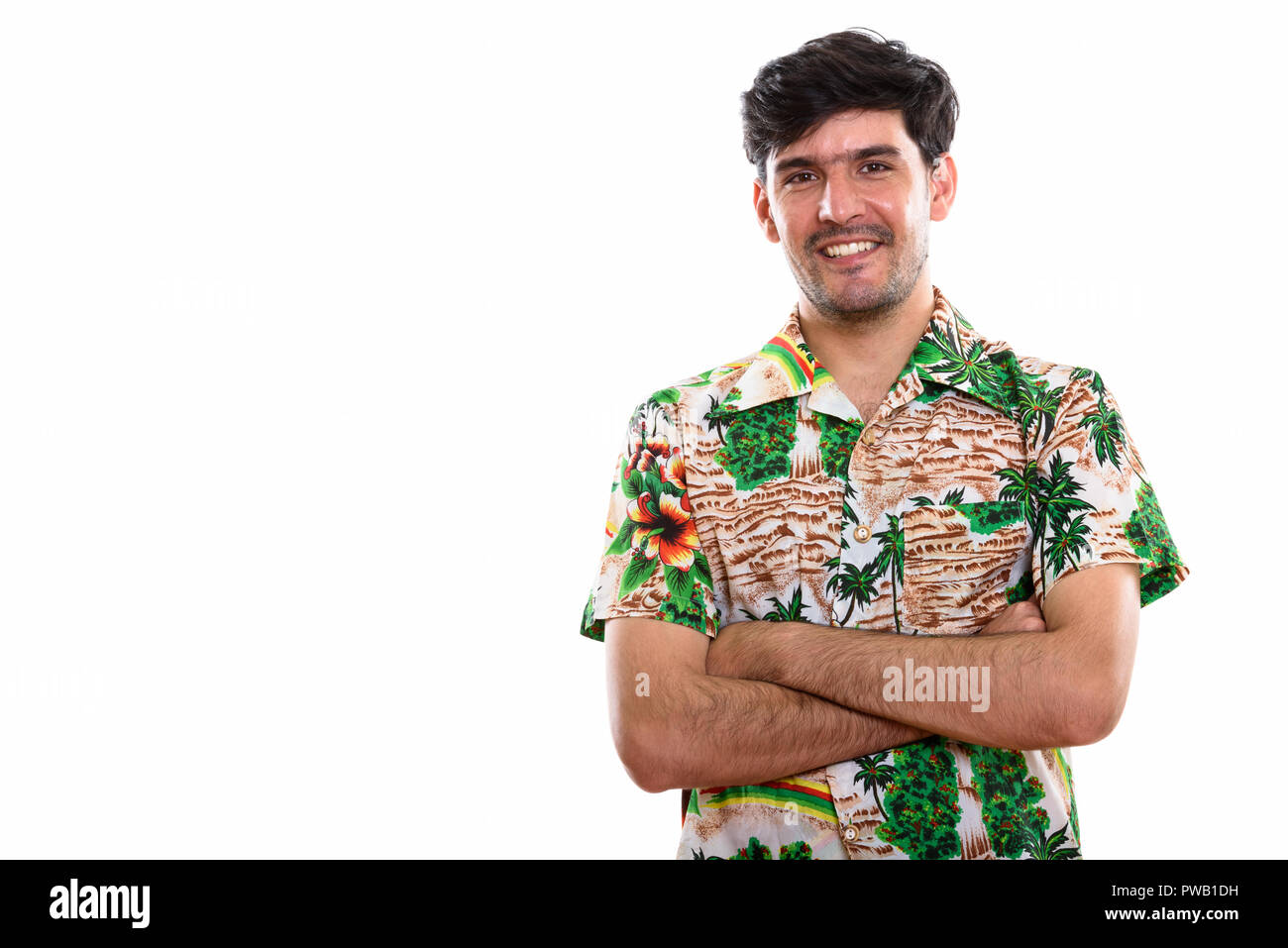 Studio shot of young happy Persian man smiling with arms crossed Stock ...