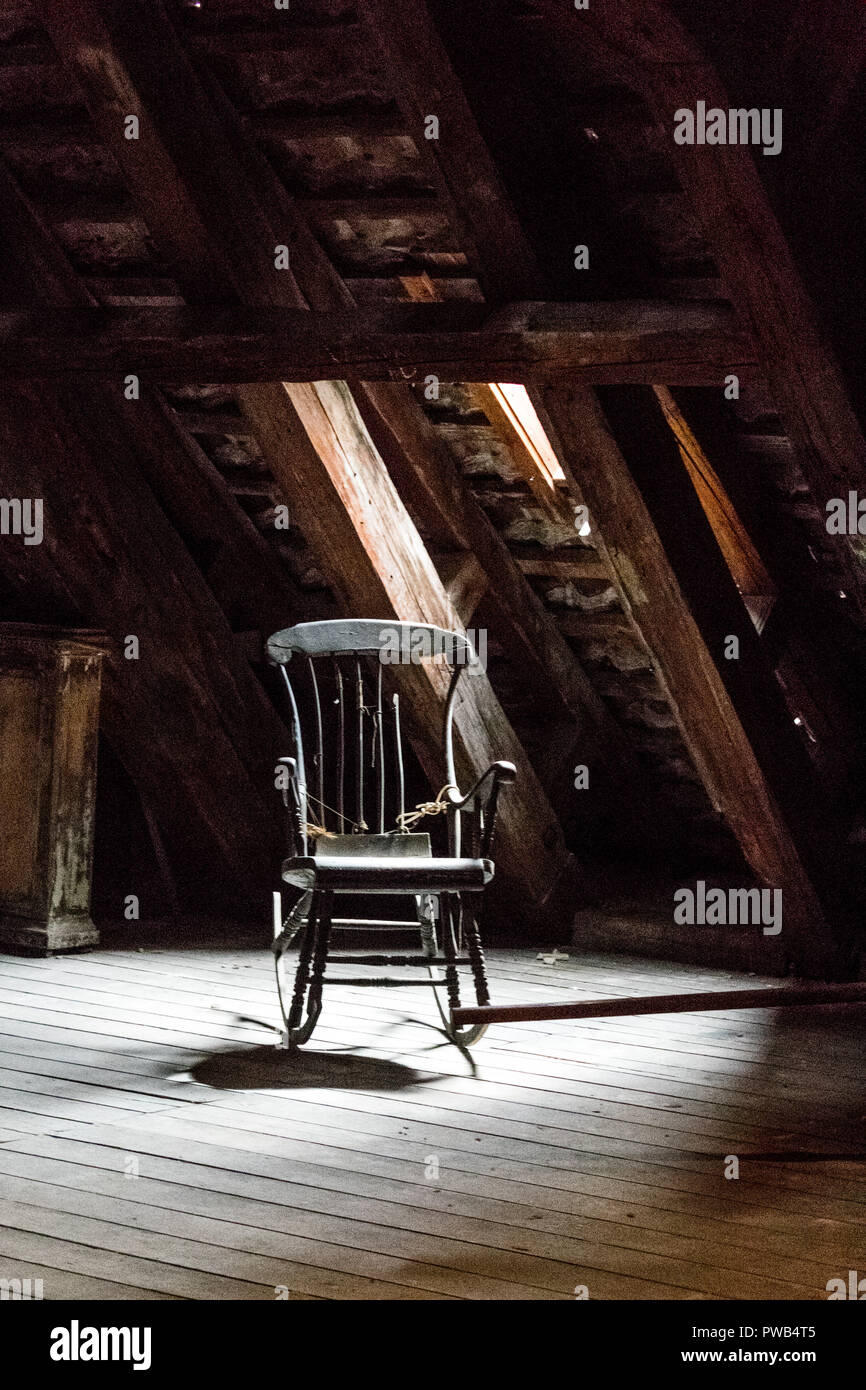 A empty rocking chair sitting next to a window, with light on it Stock ...