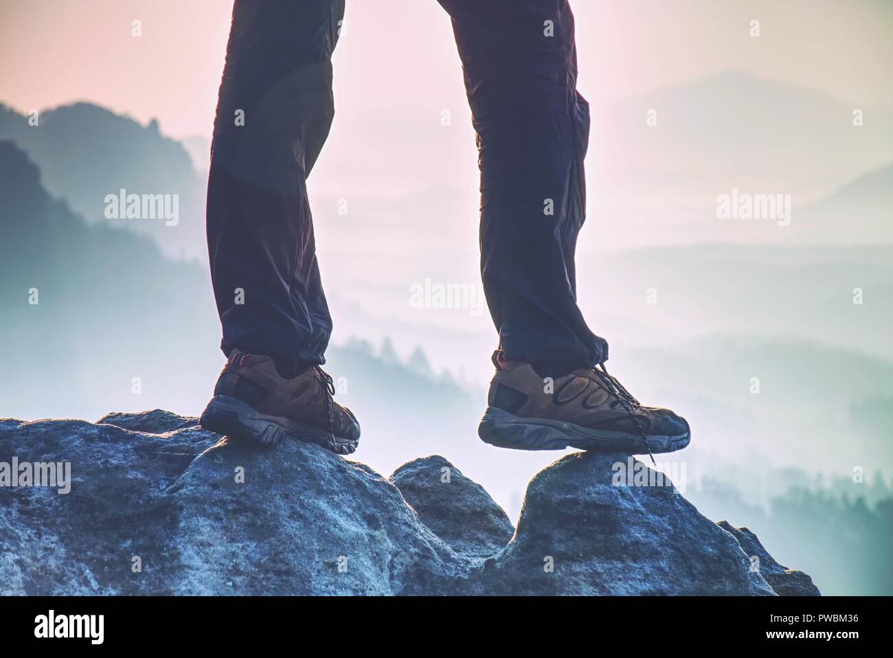 Feets and legs of hiker on peak with hiking trail and misty mountain ...