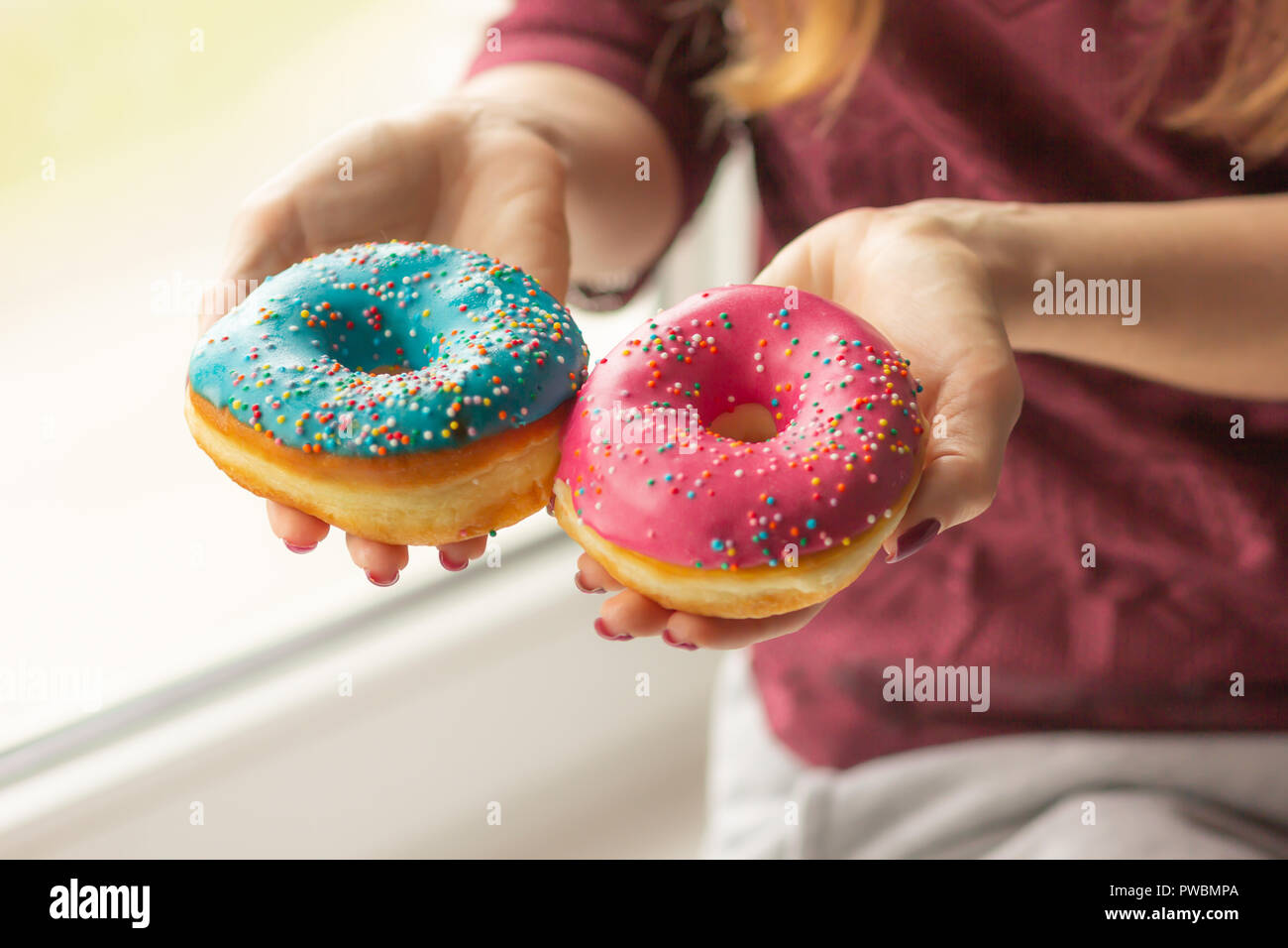 Female hands holding sweet donuts with sprinkles Stock Photo - Alamy