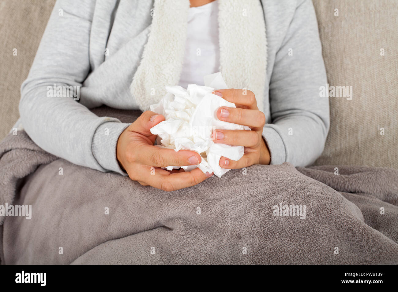 Close up picture of ill woman holding tissues after blowing her nose ...