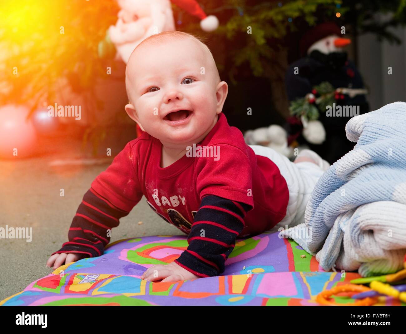 Little baby under Christmas tree, smiling and playing Stock Photo - Alamy