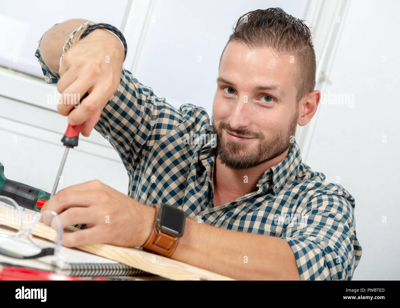 a smiling young man using screwdriver at home Stock Photo - Alamy