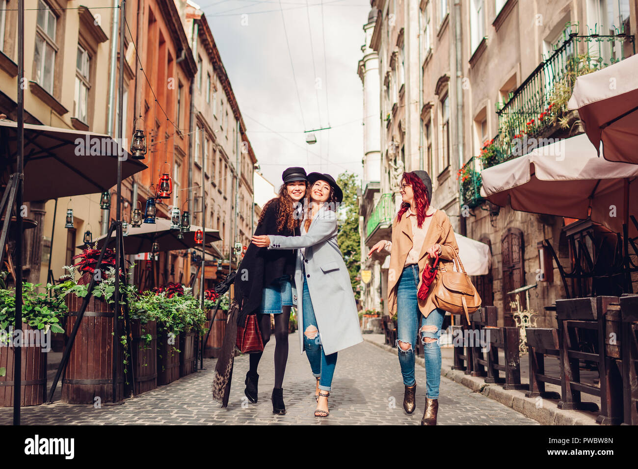 Outdoor shot of three young women walking on city street. Happy girls ...