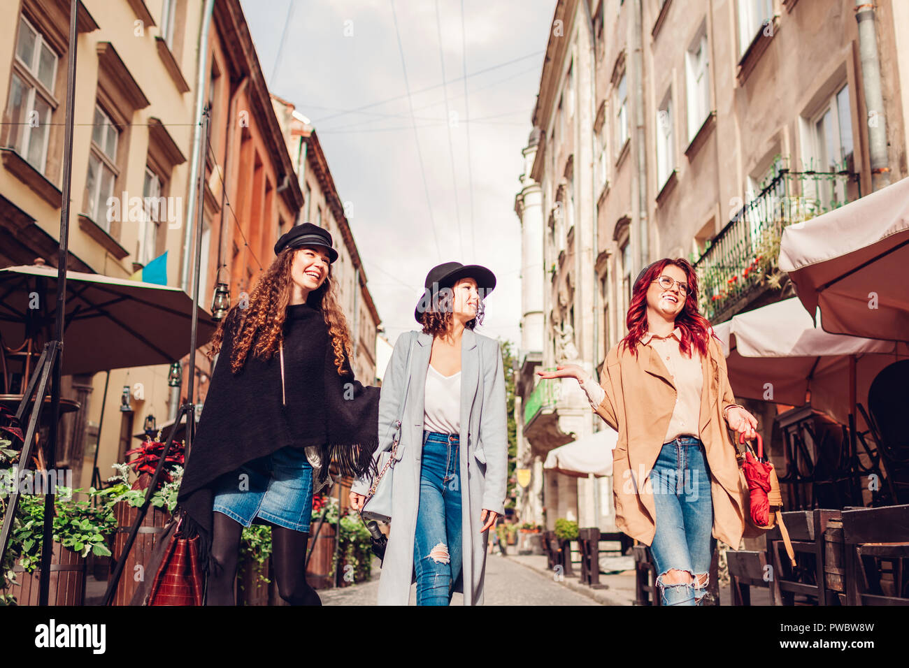 Outdoor shot of three young women walking on city street. Happy girls ...