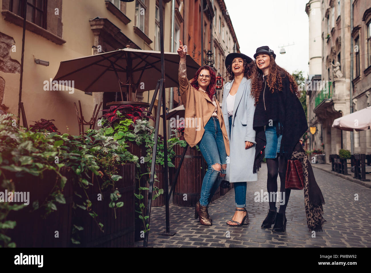 Outdoor shot of three young women walking on city street. Happy girls ...