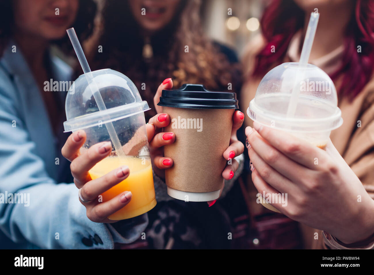 Three female friends having drinks outdoors. Happy women clinking ...