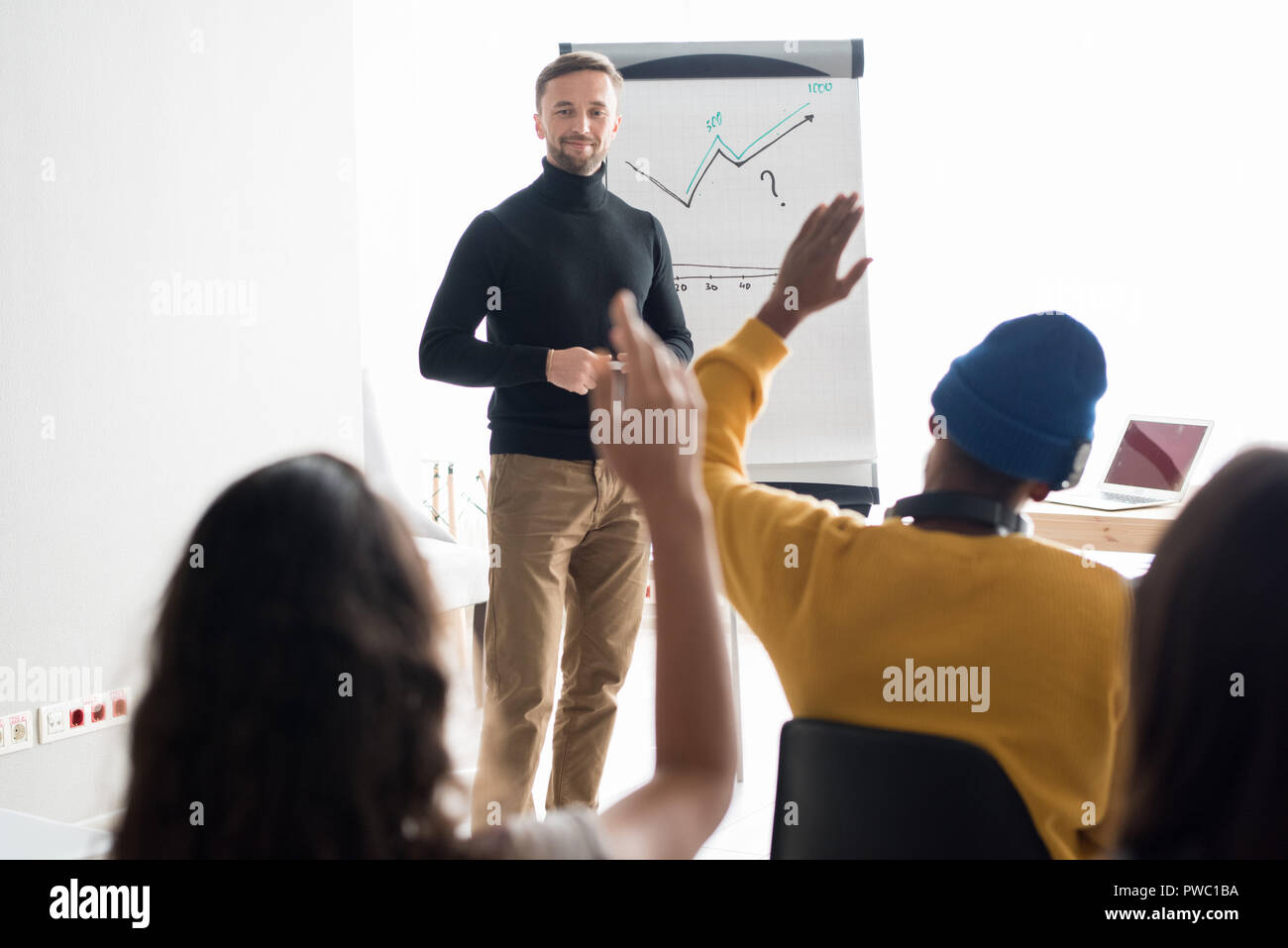 Smiling handsome young bearded speaker in black polo neck standing at ...