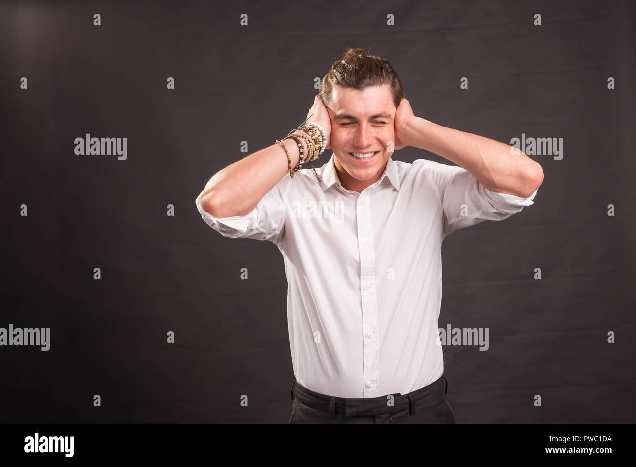 Handsome man covering his ears with both hands and looking at the ...