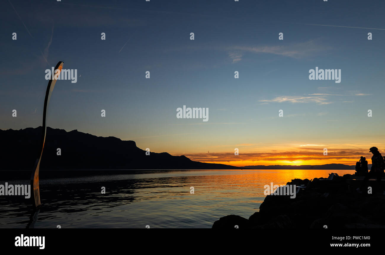Modern sculpture - big fork in water of Geneva lake at beautiful sunset ...