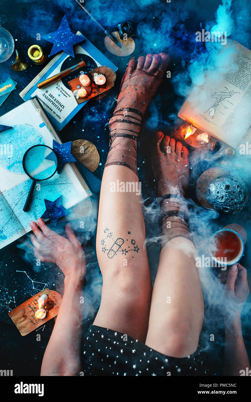 Astronomy hobby flat lay with young women legs, books, stars, and smoke ...