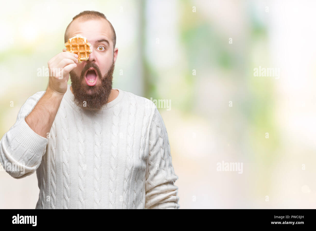 Young caucasian hipster man eating sweet waffle over isolated ...