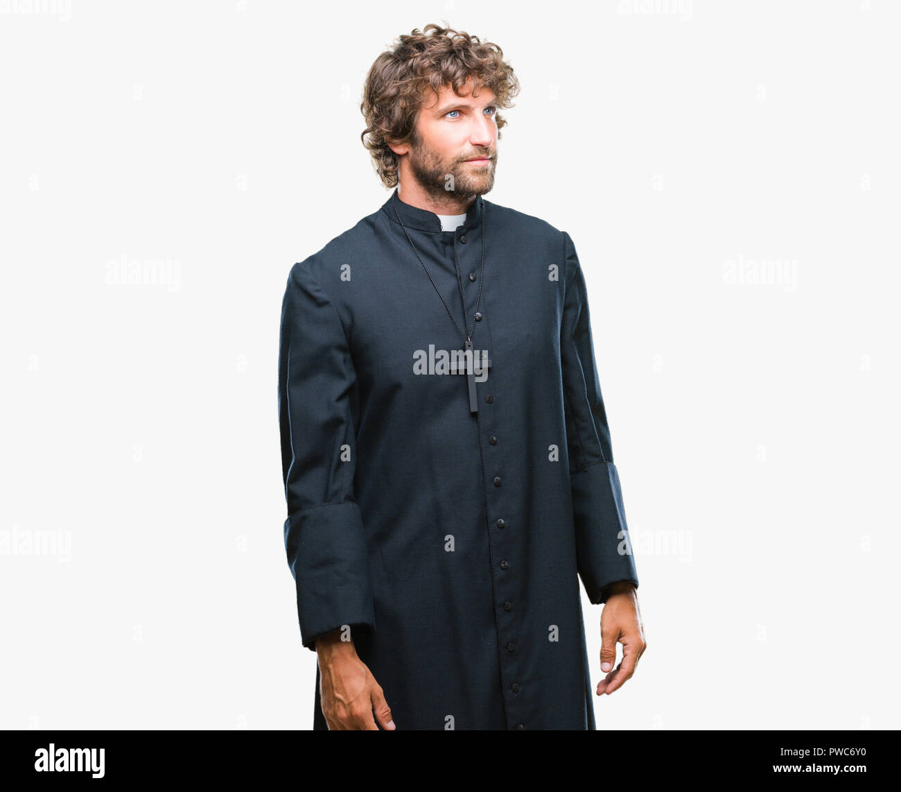 Handsome hispanic catholic priest man over isolated background looking ...