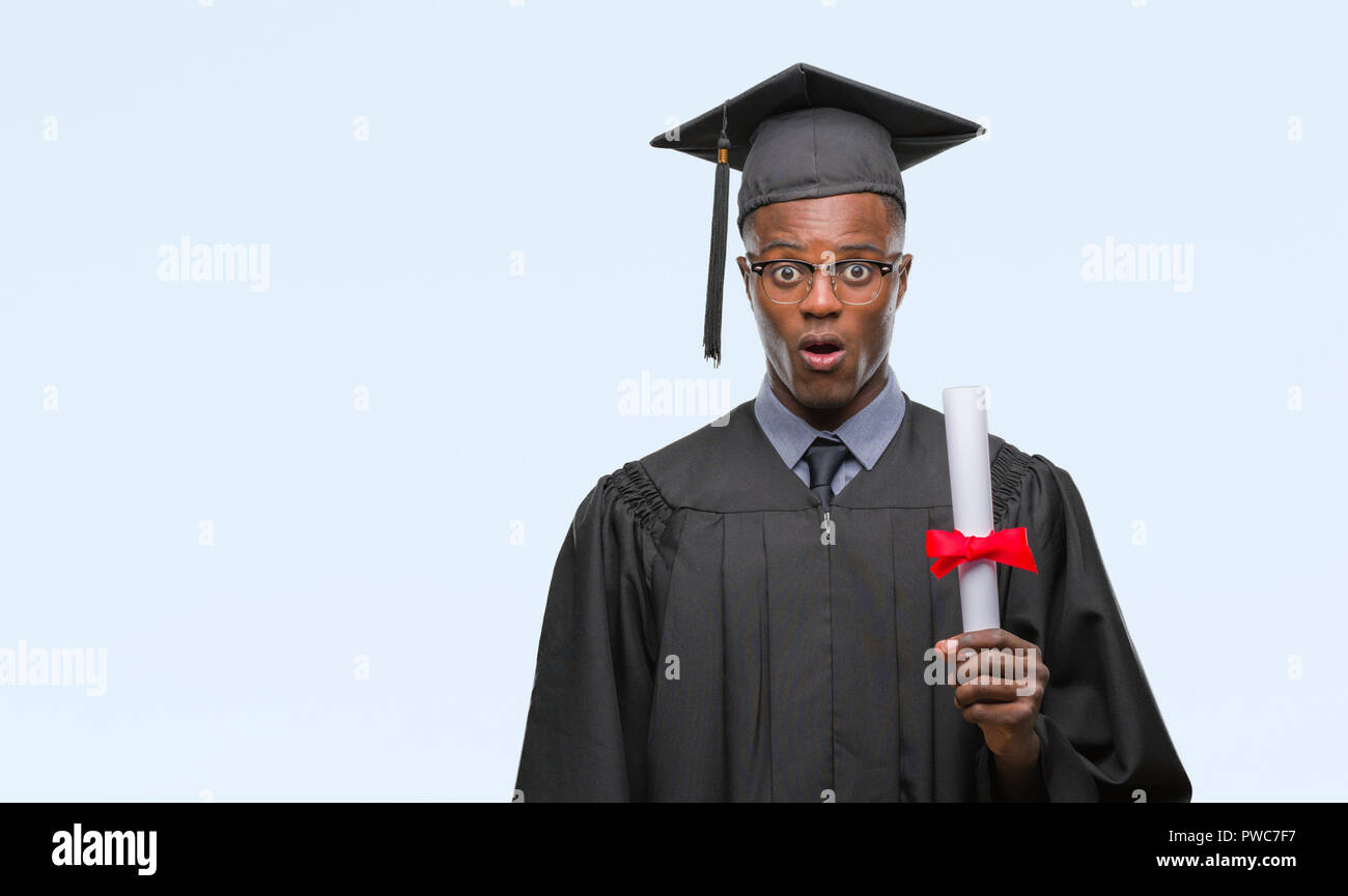 Young graduated african american man holding degree over isolated ...