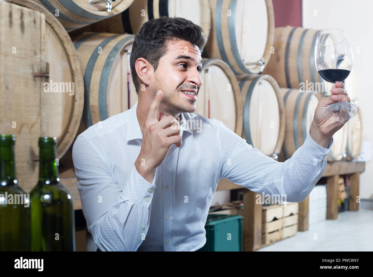 portrait of happy russian man tasting wine sample in glass in alcohol ...