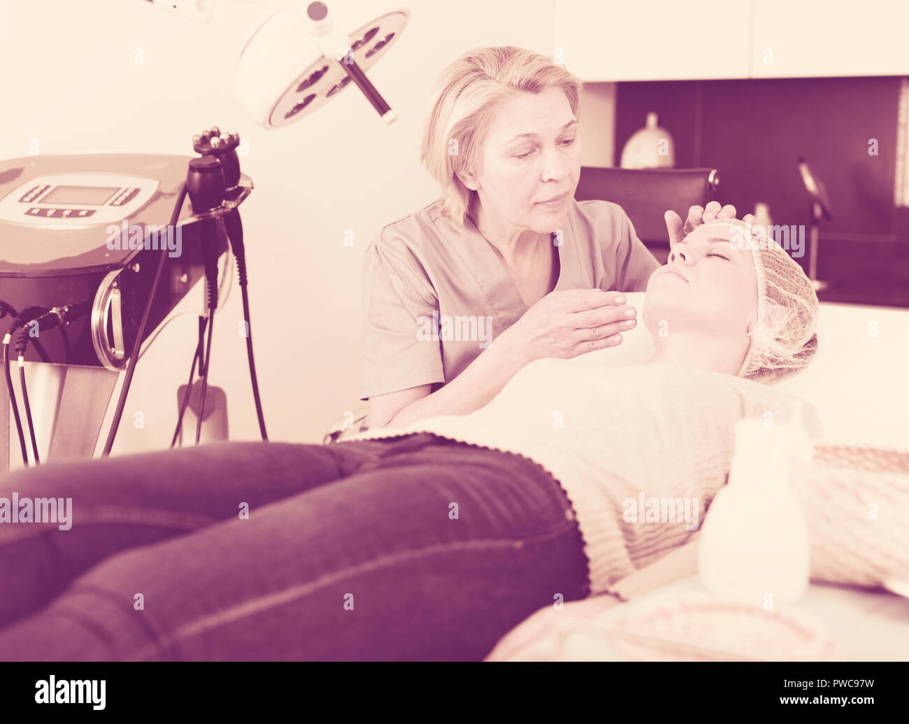 Professional cosmetician examining face skin of girl in clinic of ...