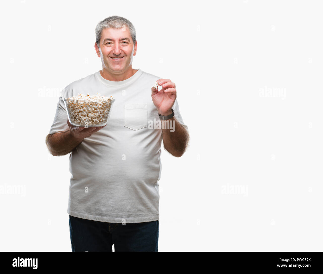 Handsome senior man eating popcorn over isolated background with a ...