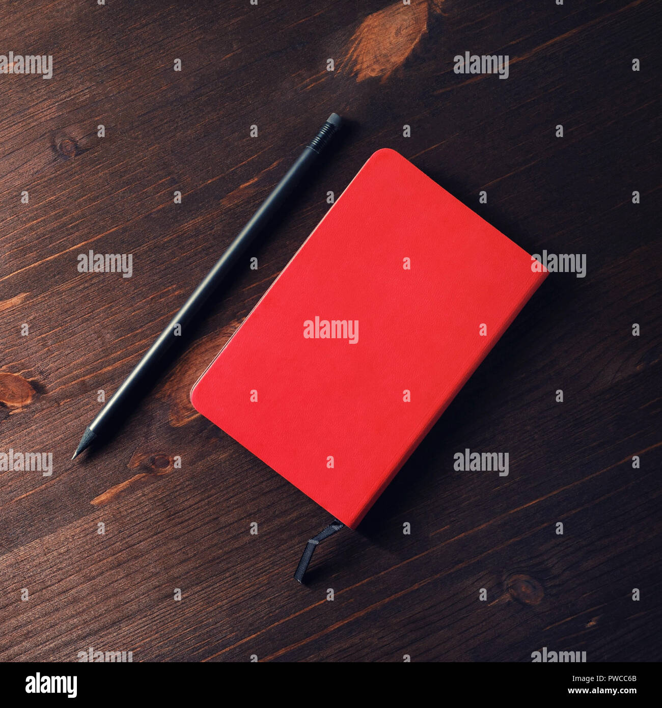 Red notepad and pencil on dark wood table background. Flat lay Stock ...