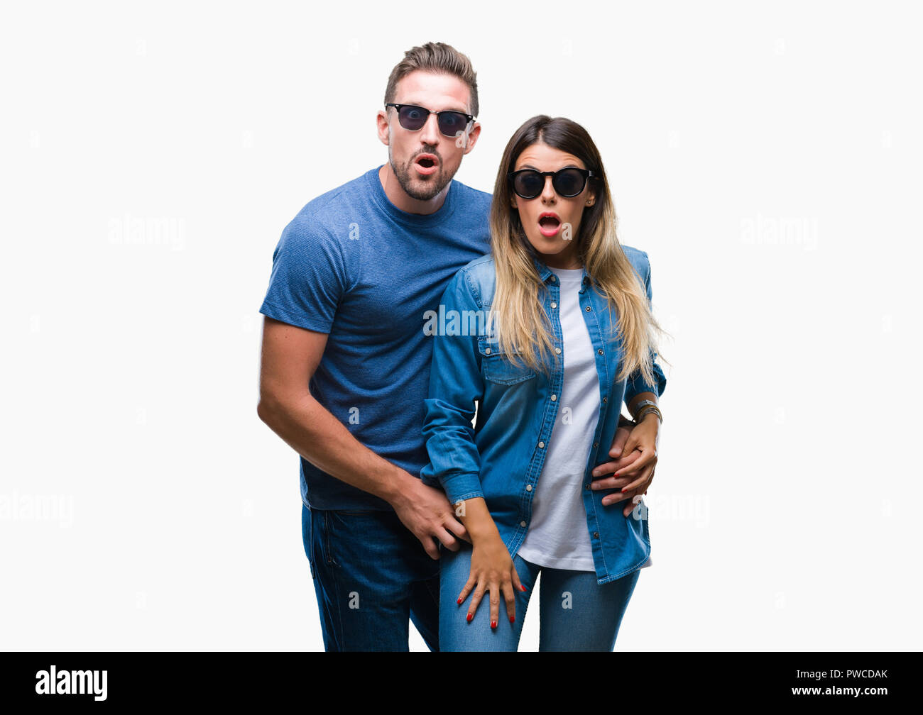Young couple in love wearing sunglasses over isolated background afraid ...