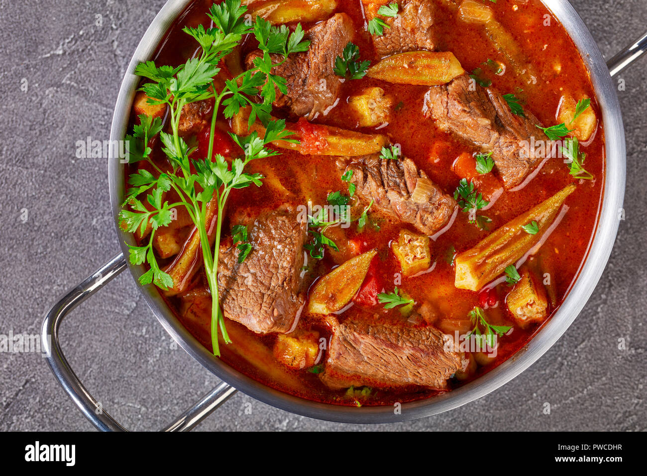 overhead view of hearty Beef and Okra Stew in a metal casserole on a ...