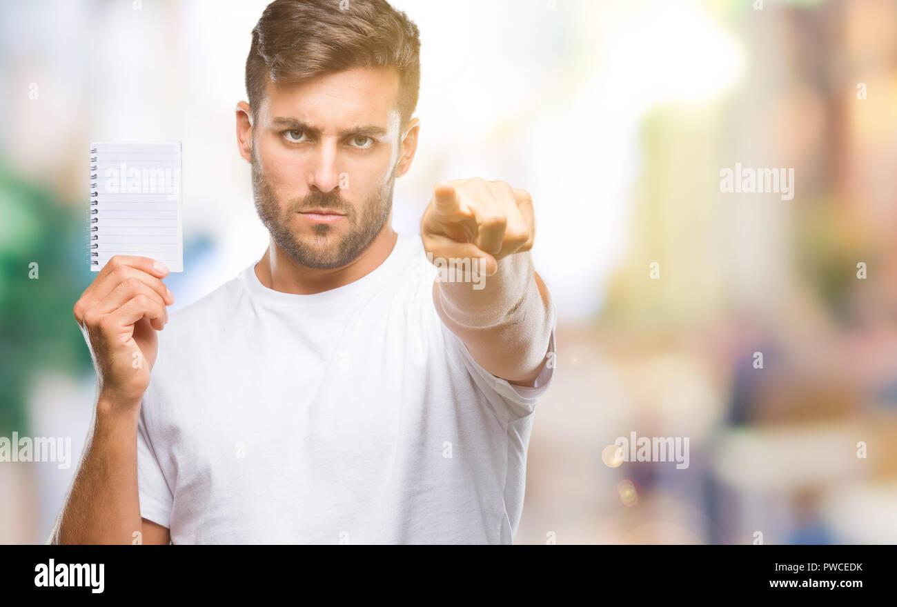 Young handsome man holding notebook over isolated background pointing ...