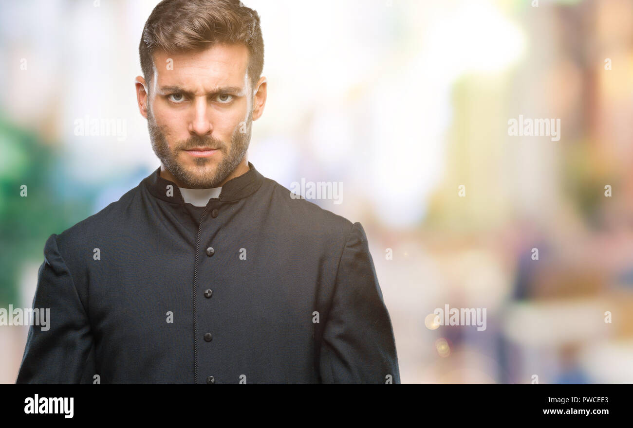 Young catholic christian priest man over isolated background skeptic ...