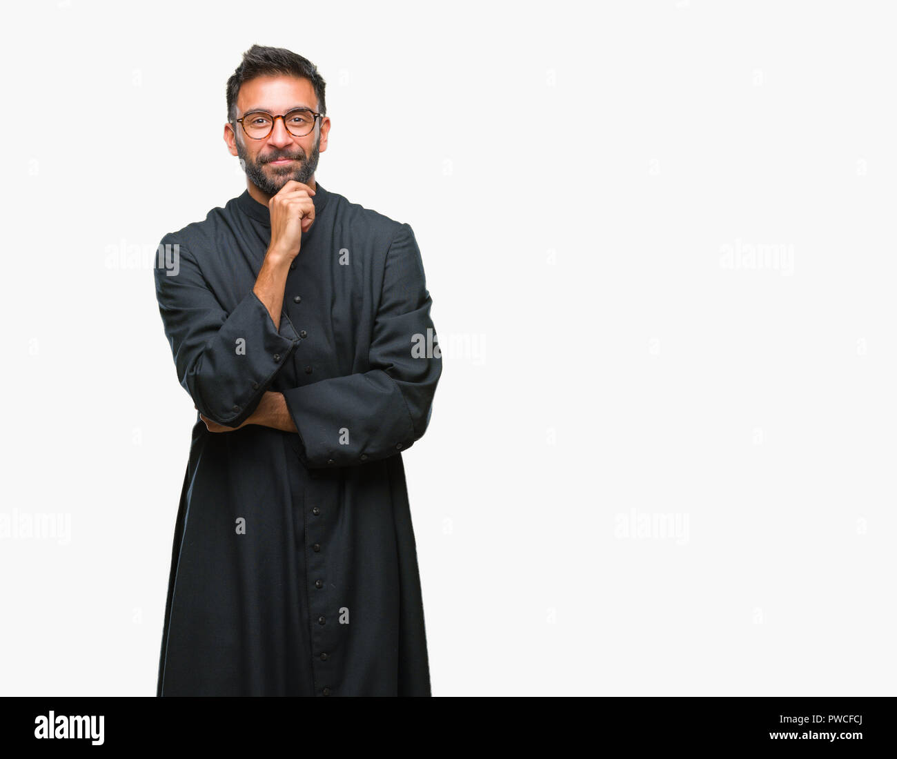 Adult hispanic catholic priest man over isolated background looking ...