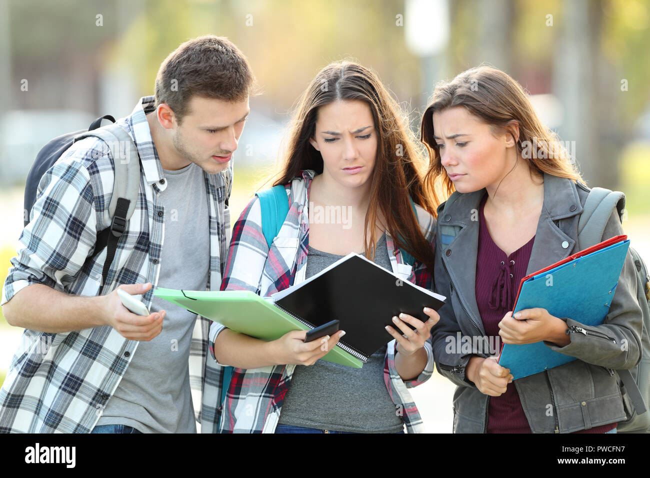 Three confused students checking paper notes before exam Stock Photo ...