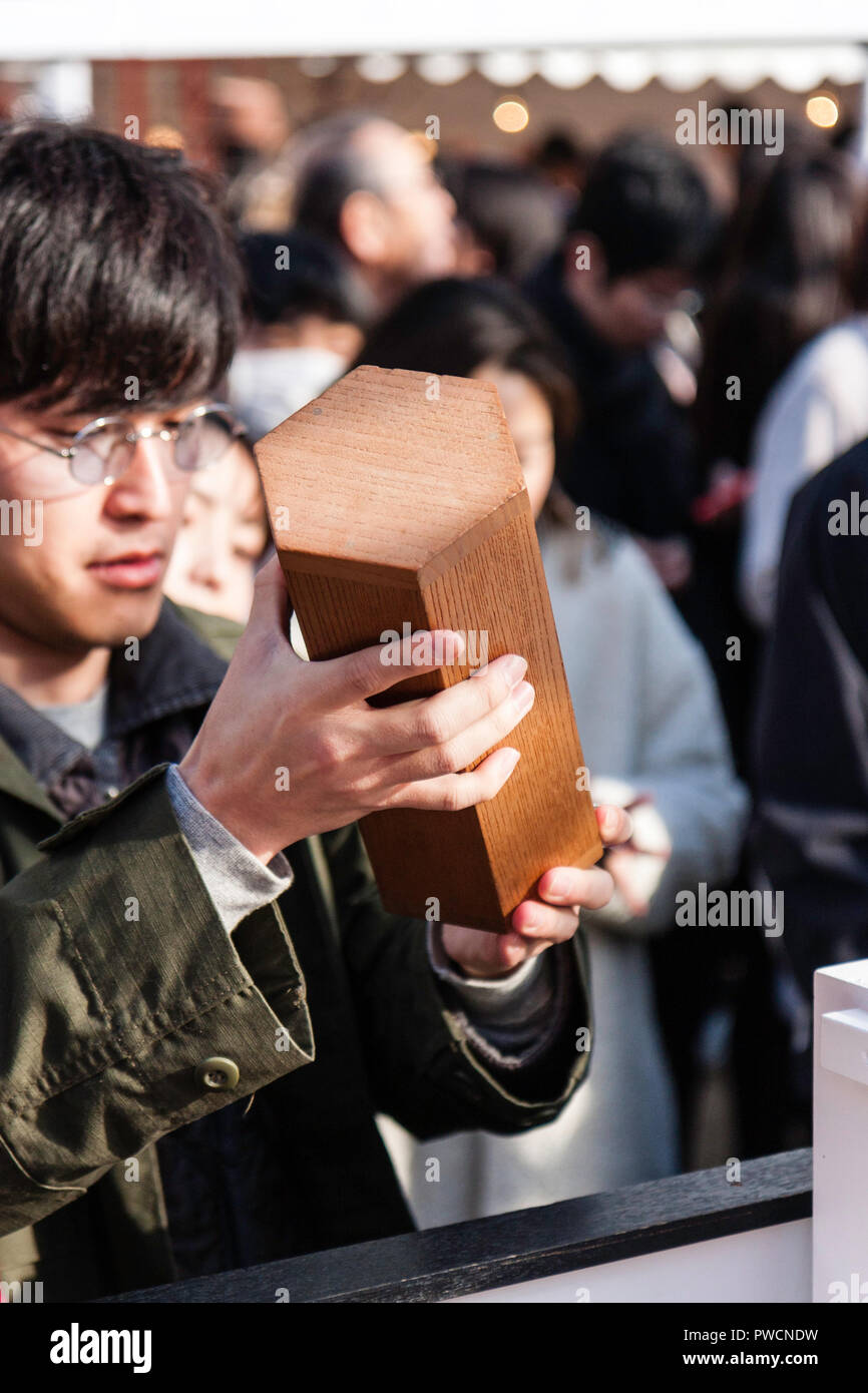 Japanese new year, shogatsu. Close up of male hands holding Omikuji box ...