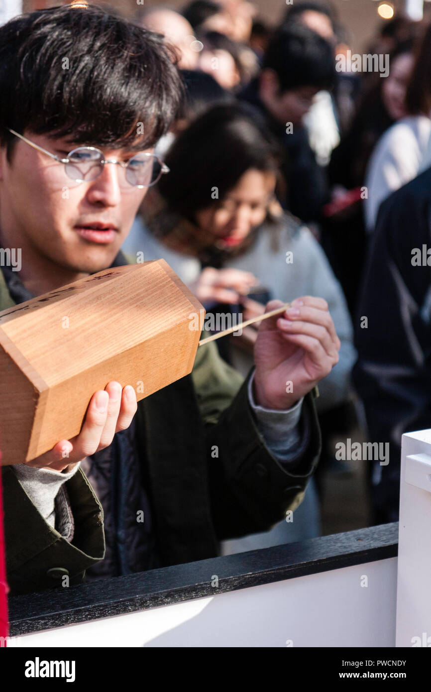 Japanese new year, shogatsu. Close up of male hands holding Omikuji box ...