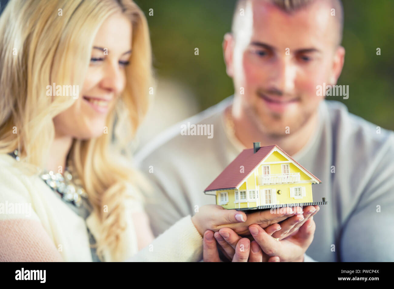 Young loving couple holding small model house Stock Photo - Alamy